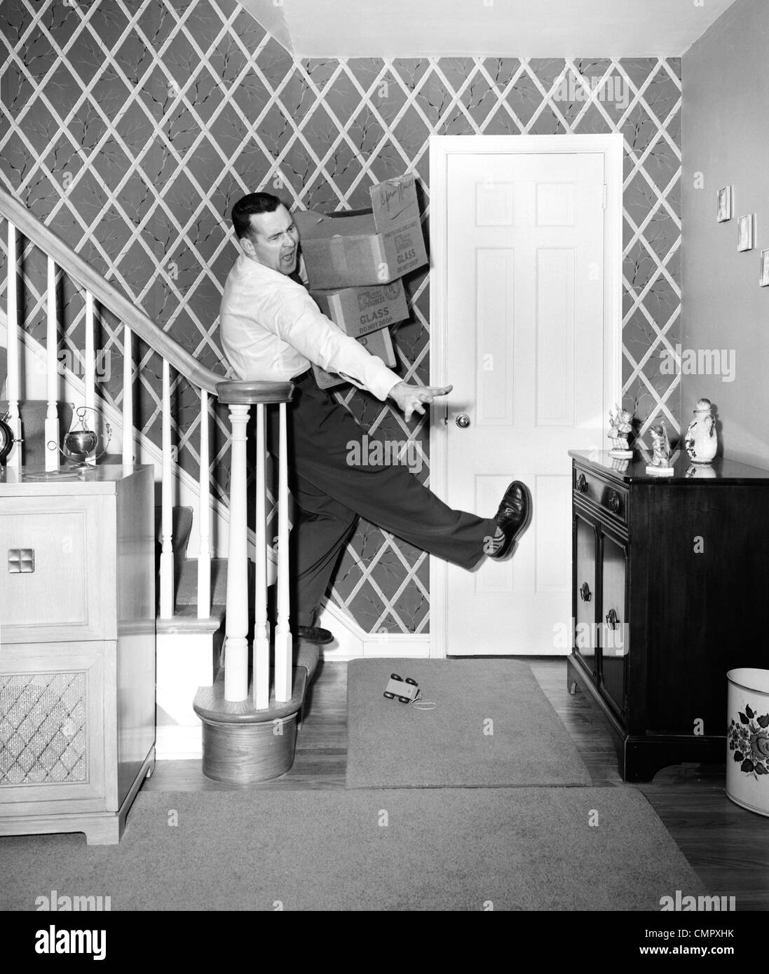 1950s MAN CARRYING STORAGE BOXES DOWN STAIRS TRIPPING AND FALLING ON ...