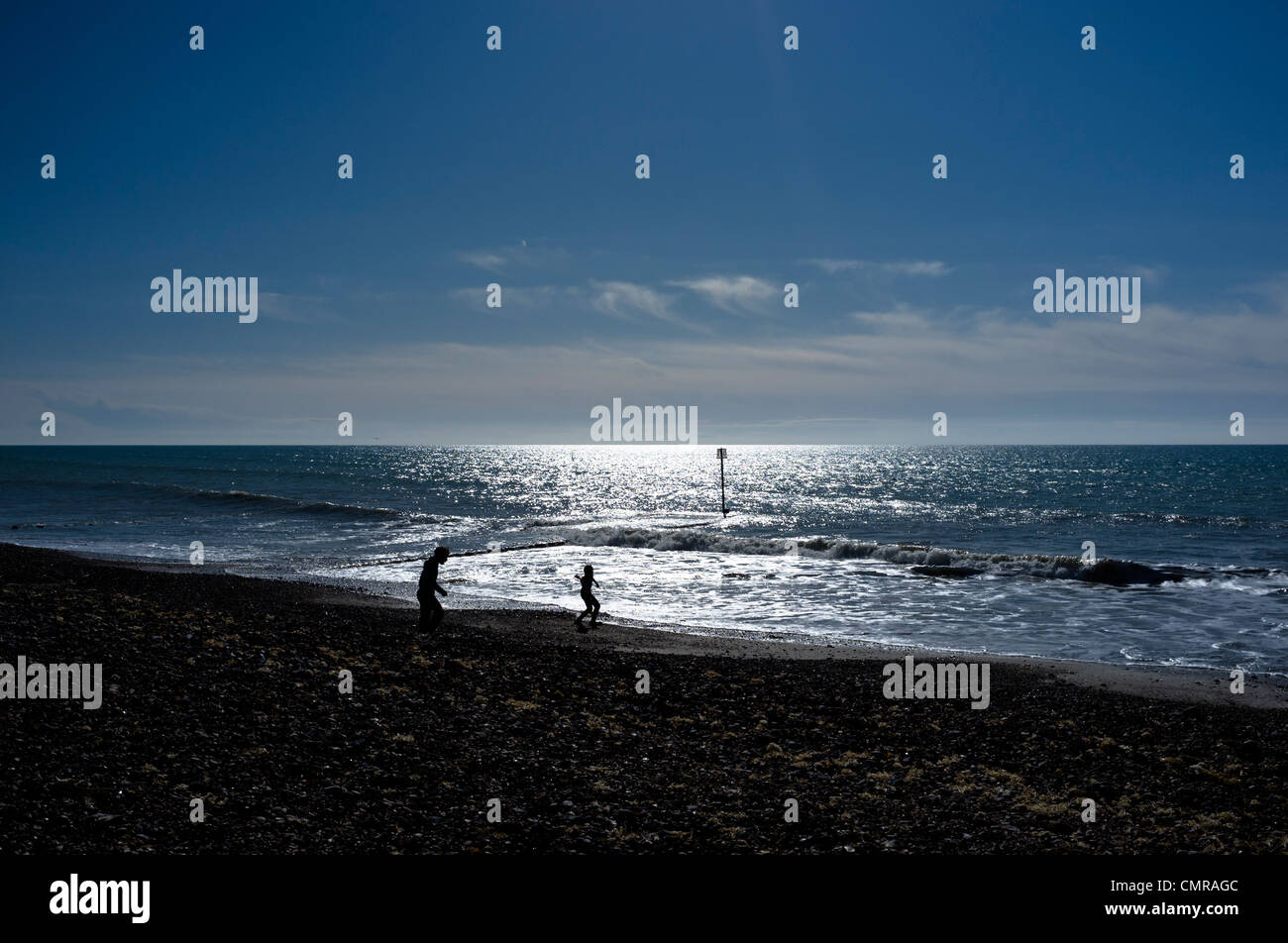 Two boys (teenagers) play on the beach, throwing stones into the sea ...