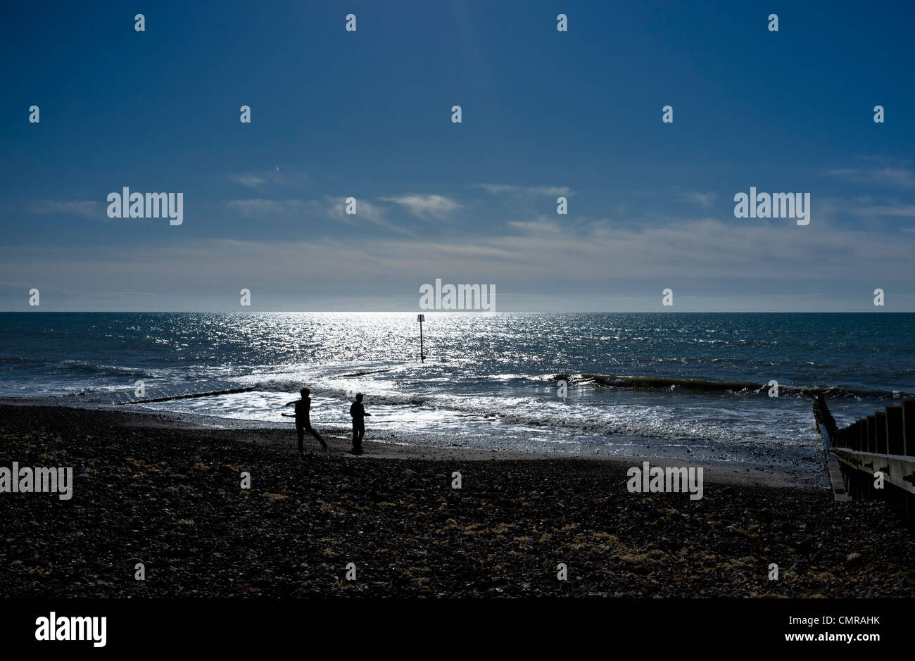 Two boys (teenagers) play on the beach, throwing stones into the sea ...