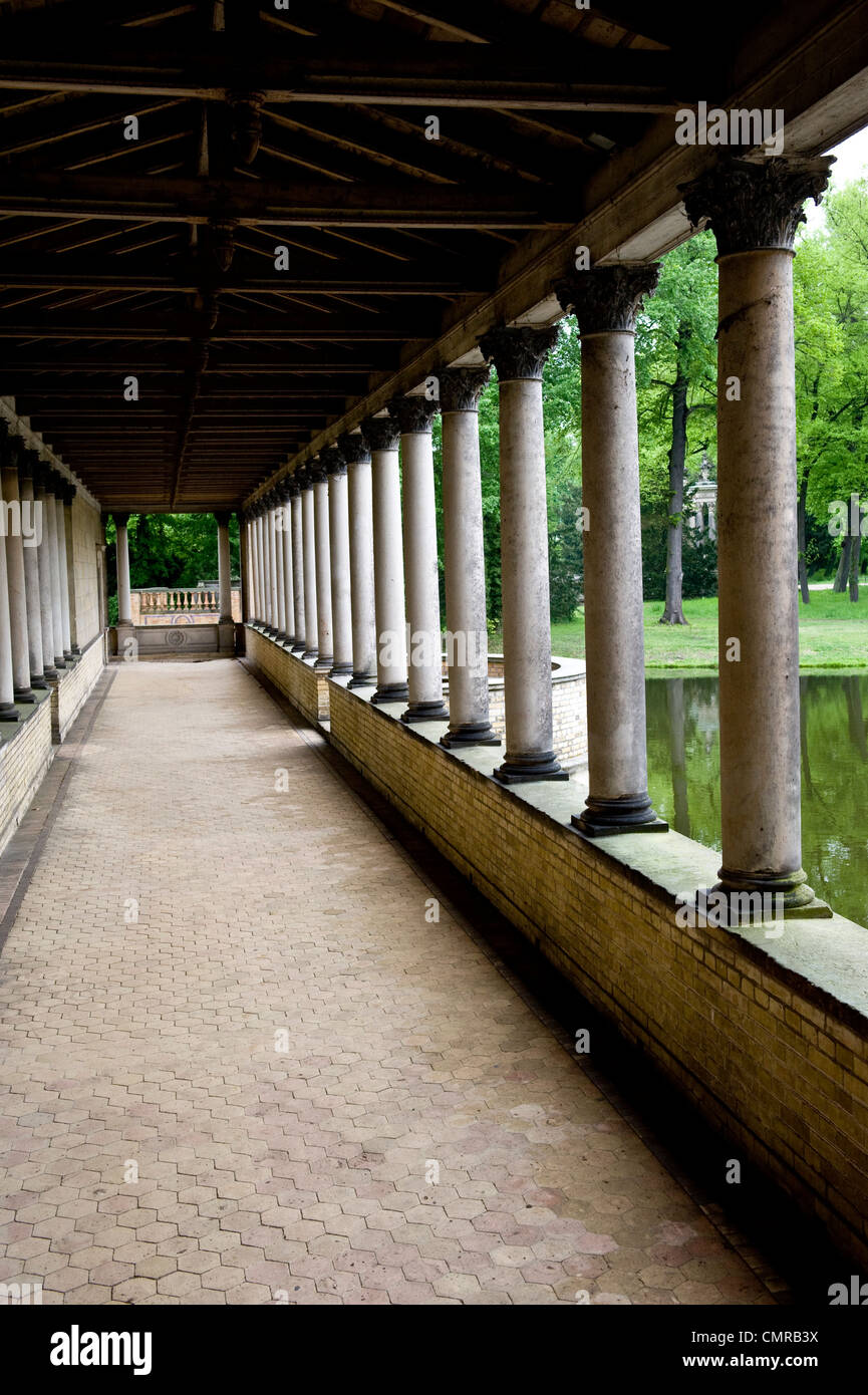 An extremely long shot under a brick, fortified walkway beside a pond ...
