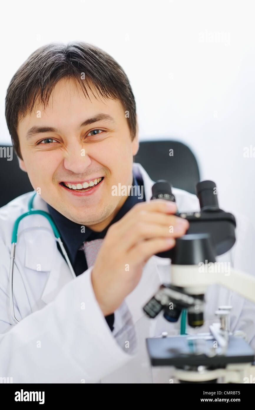 Smiling male doctor working with microscope Stock Photo - Alamy