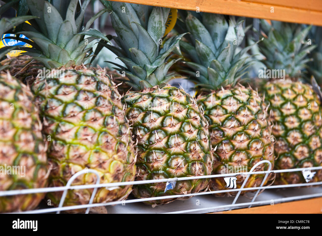 Rows of pineapple lined across a rack in the supermarket Stock Photo ...