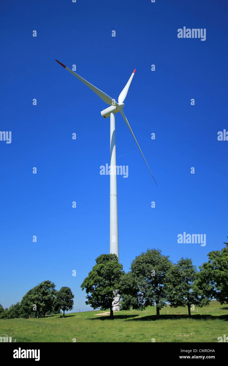 Red and white wind turbine surrounded with trees and green grass by ...
