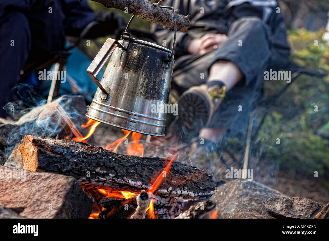 People enjoying a campfire while making a pot of boiling water Stock ...
