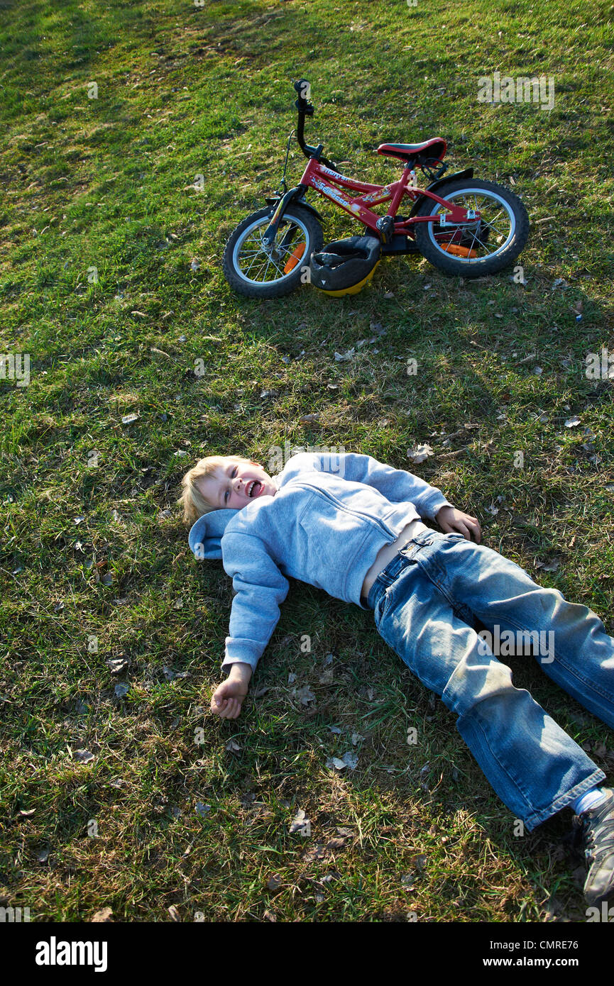 Child Blond Boy with bicycle having a rest, lying on grass field Stock ...