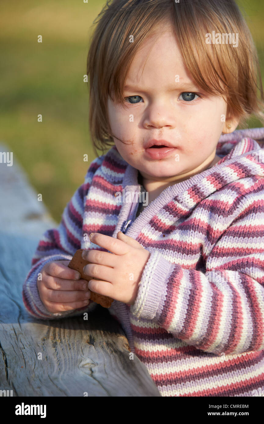 Toddler child baby girl eating cracker outside Stock Photo - Alamy