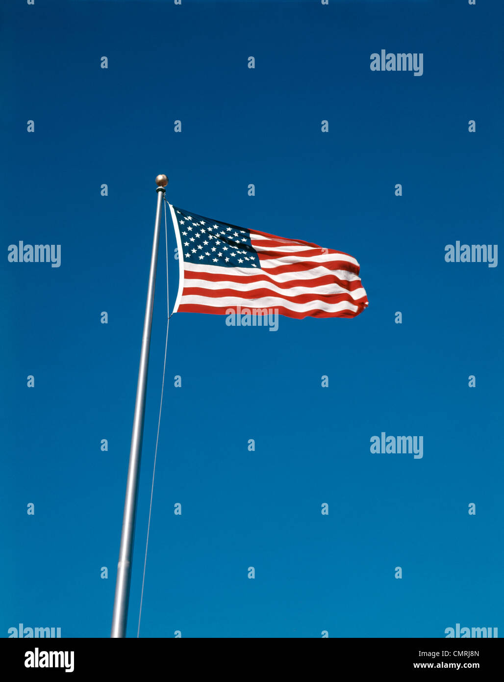 1980s UNITED STATES FLAG FLYING ON FLAGPOLE IN BLUE CLOUDLESS SKY Stock ...