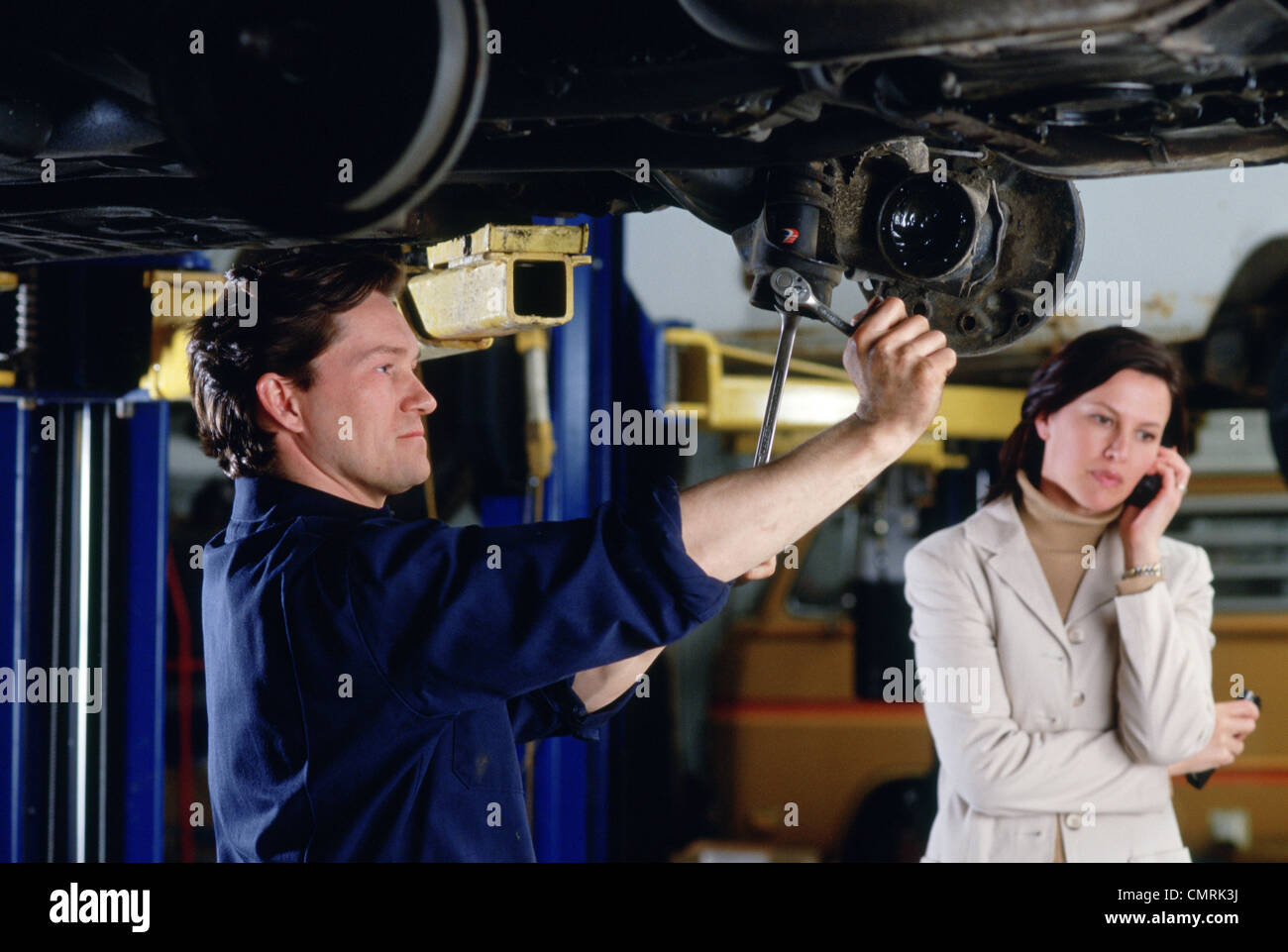 Mechanic Working on Car while Woman Waits Stock Photo - Alamy