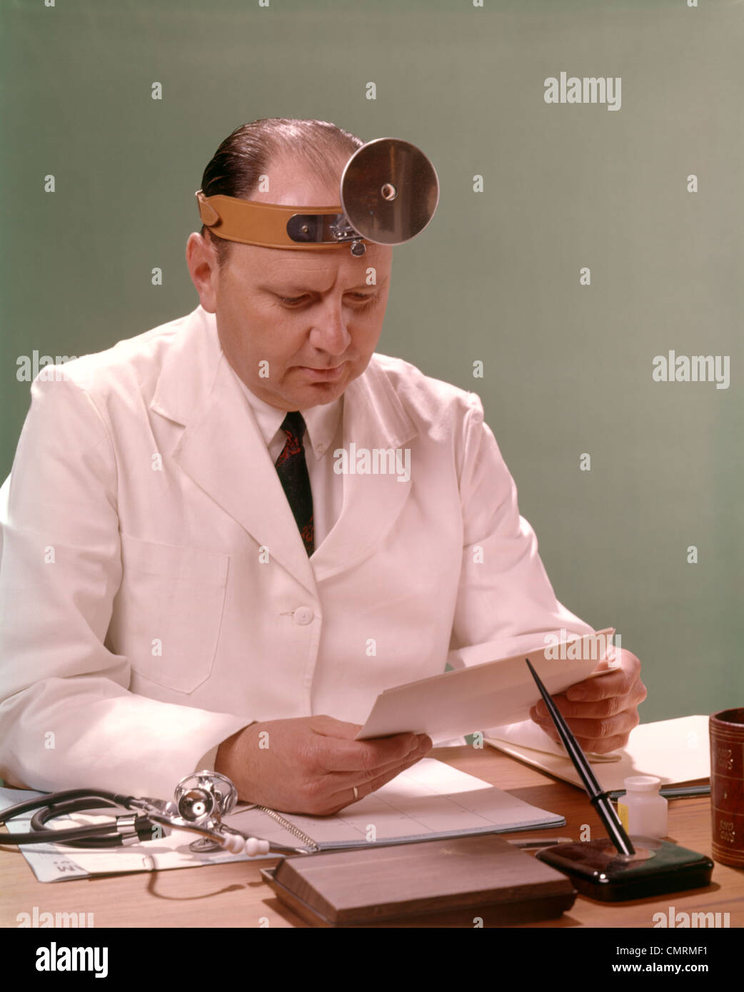 1960s DOCTOR LOOKING AT PAPERWORK IN OFFICE Stock Photo - Alamy