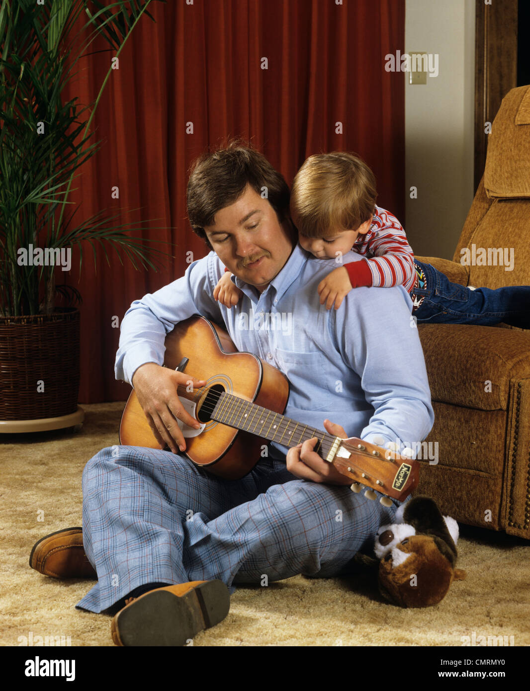1980s FATHER PLAYING ACOUSTIC GUITAR FOR SON IN LIVING ROOM Stock Photo ...