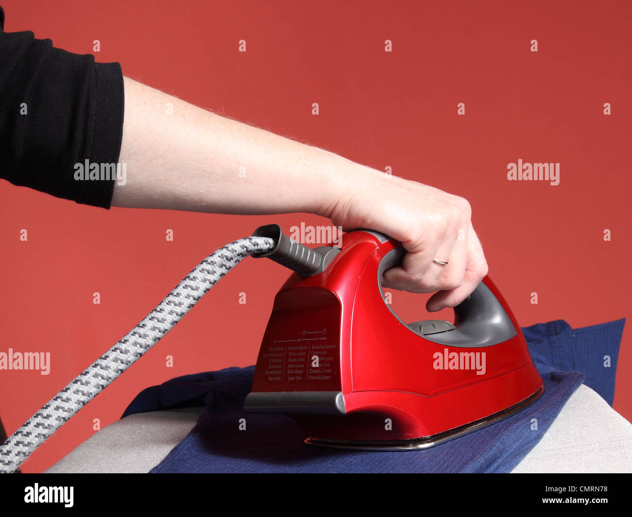 household chores - red iron in hand and navy blue shirt Stock Photo - Alamy