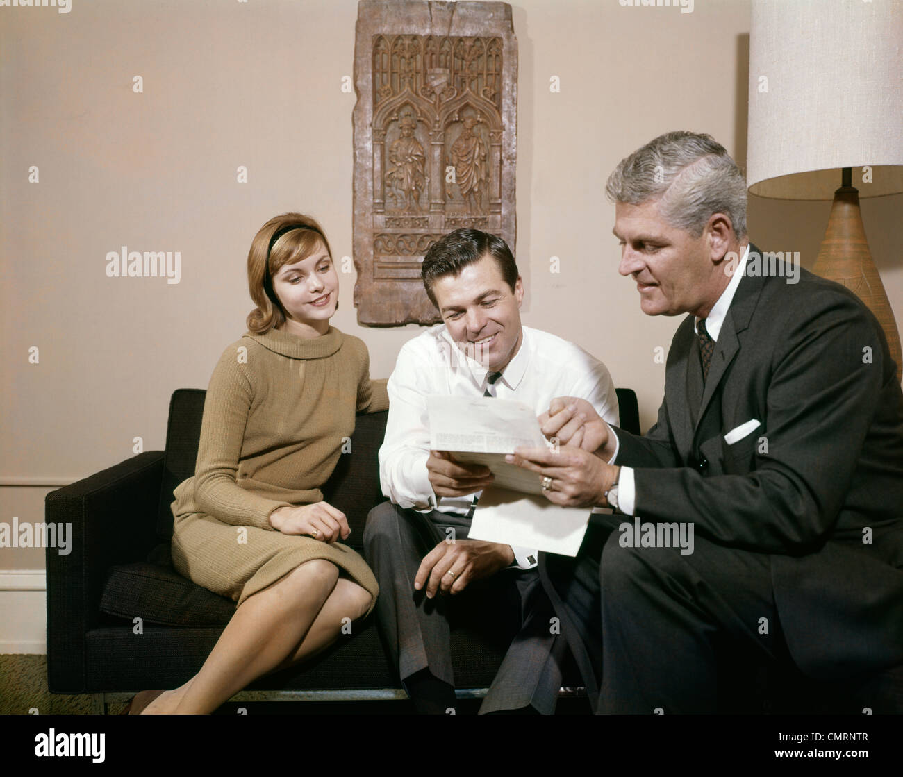 1960s COUPLE MAN WOMAN LIVING ROOM TALKING TO SALESMAN LOOKING CONTRACT ...