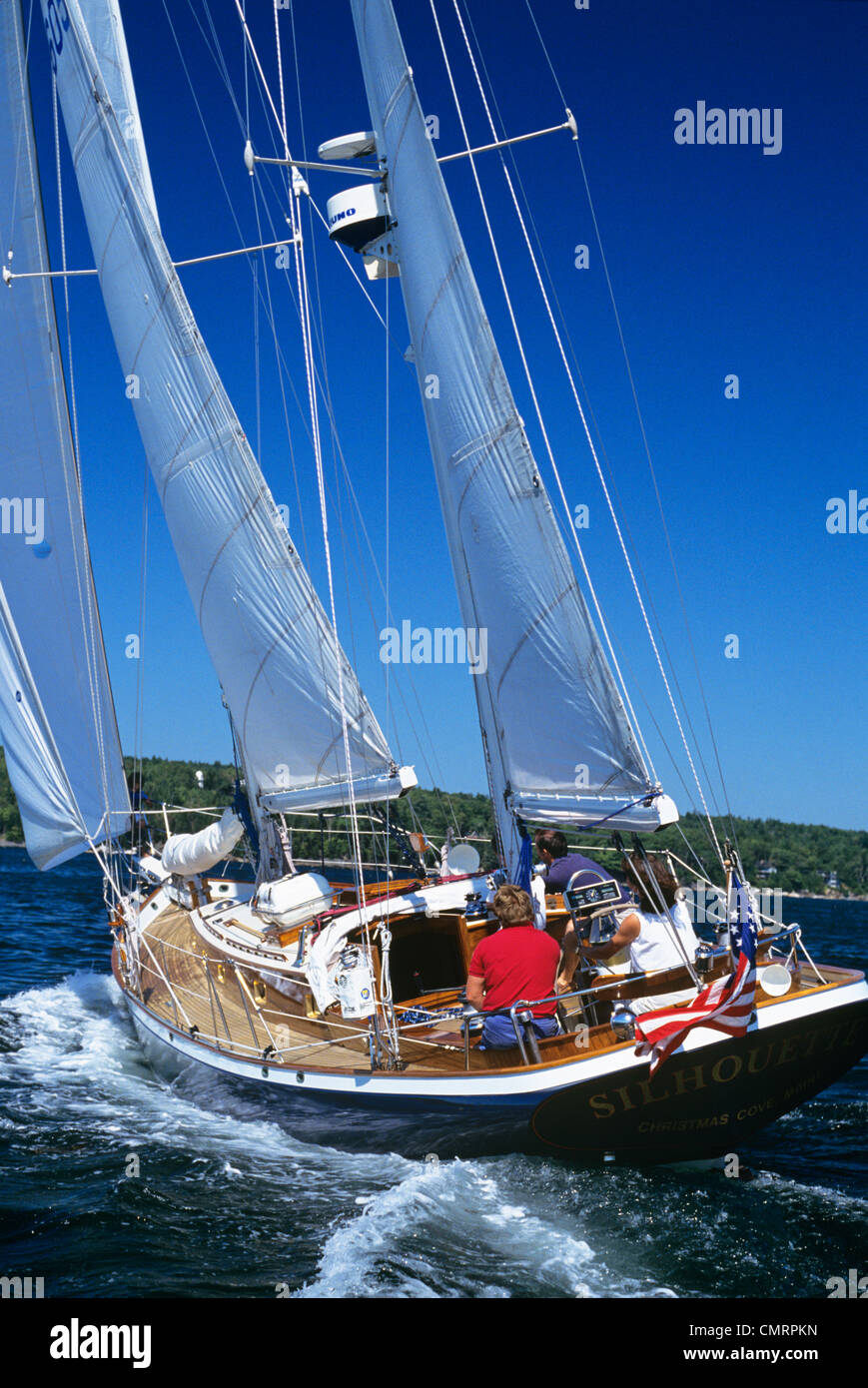 THREE PEOPLE ON SAILBOAT SAILING VIEW FROM STERN Stock Photo - Alamy