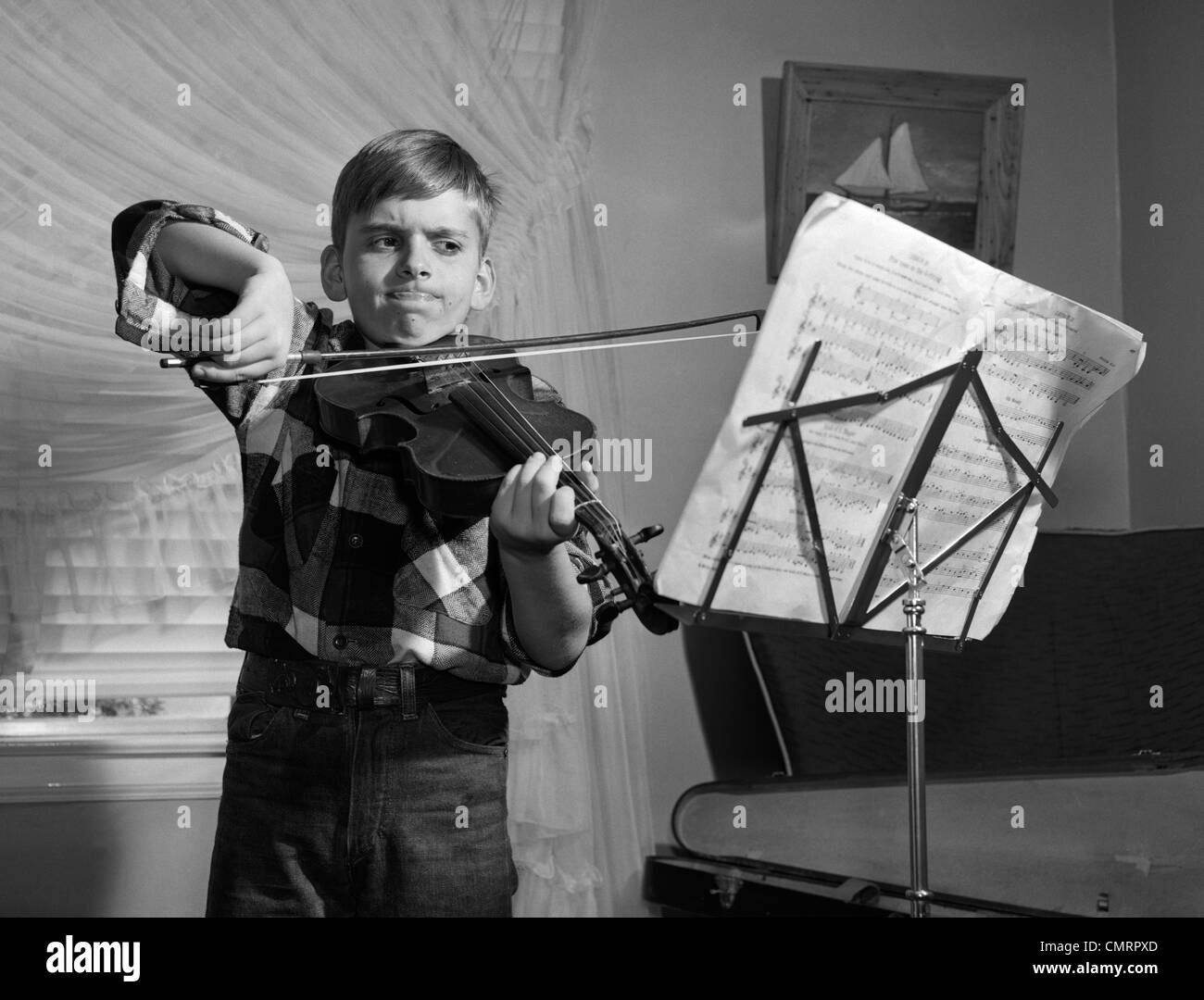 1950s BOY IN LIVING ROOM PRACTICING VIOLIN WITH DETERMINED EXPRESSION ...
