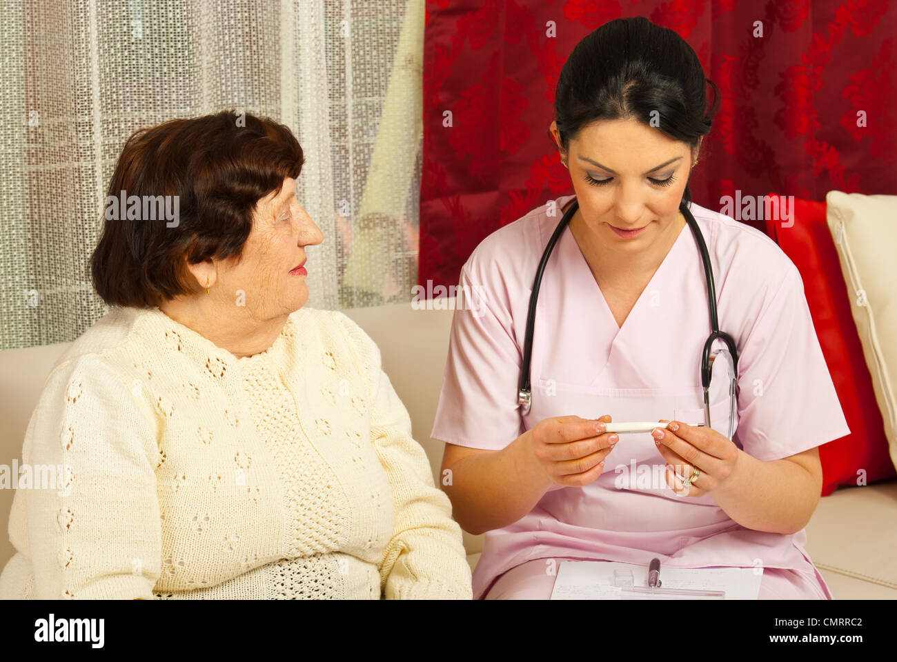 Nurse checking temperature to senior woman in her home Stock Photo - Alamy