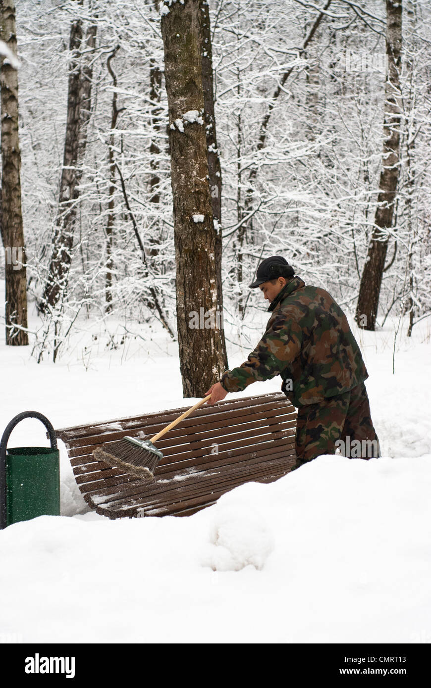 A man cleaning the bench covered by snow Stock Photo - Alamy