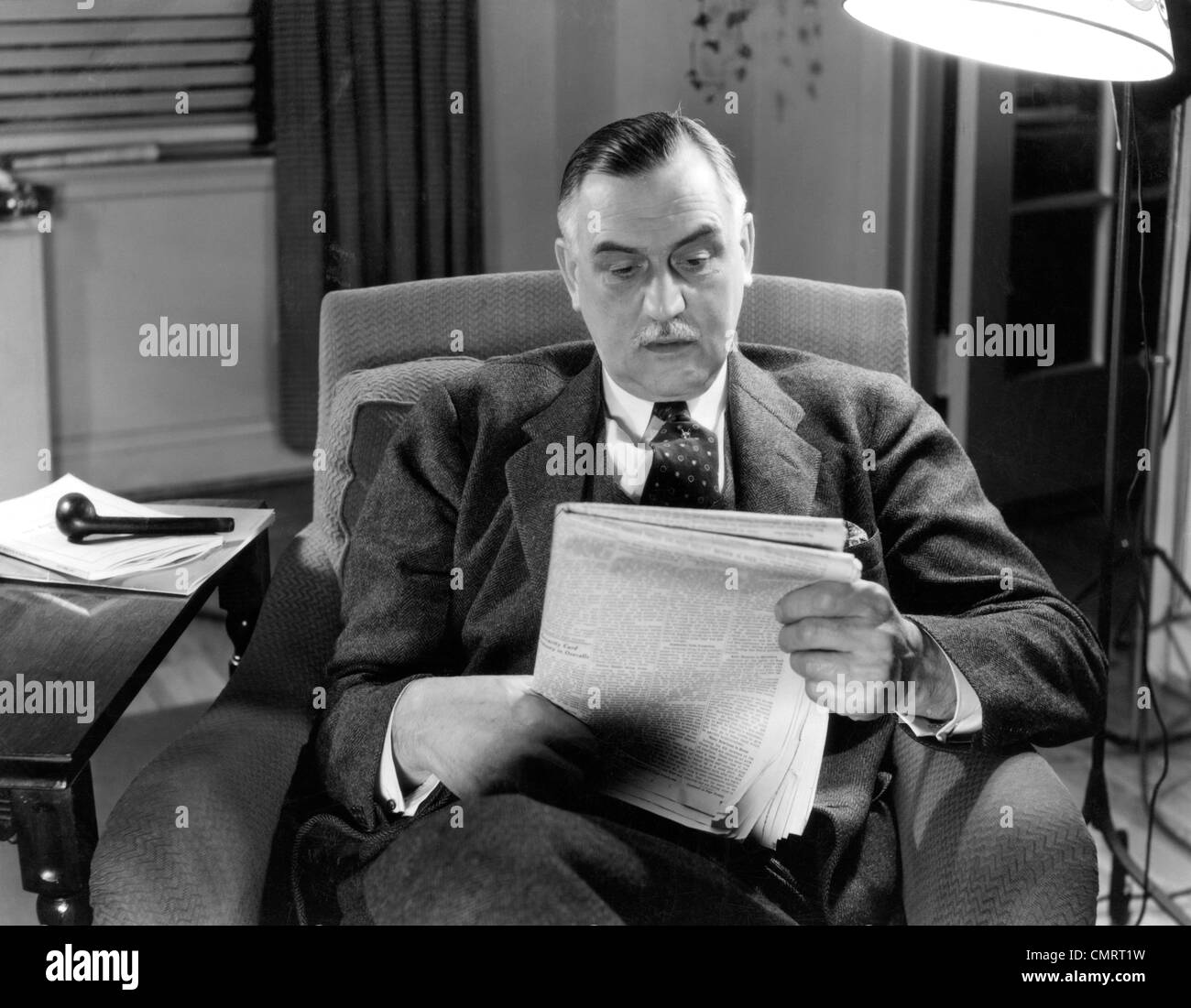 1930s 1940s OLDER BUSINESSMAN SITTING IN CHAIR READING NEWSPAPER Stock ...