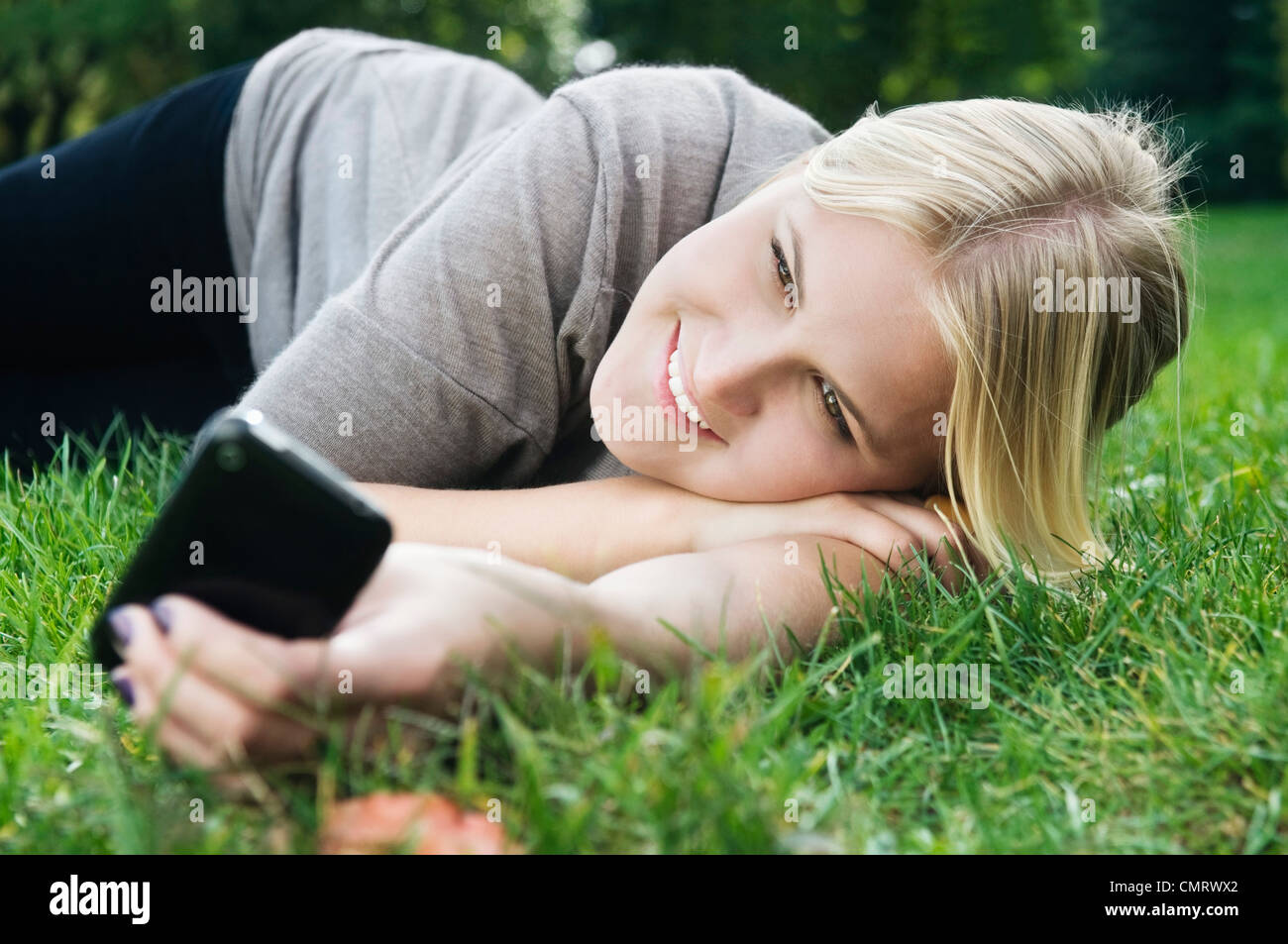 Happy girl on lawn with phone Stock Photo - Alamy