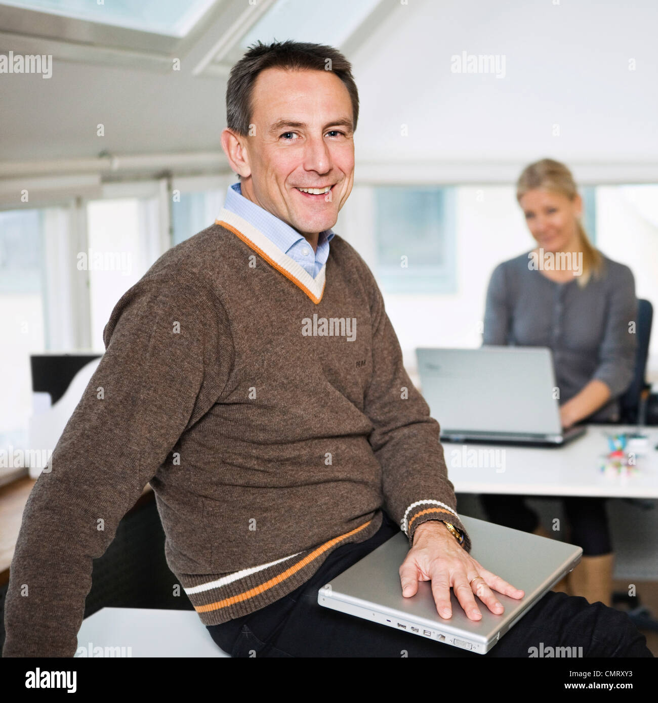 Man sitting on desk Stock Photo - Alamy