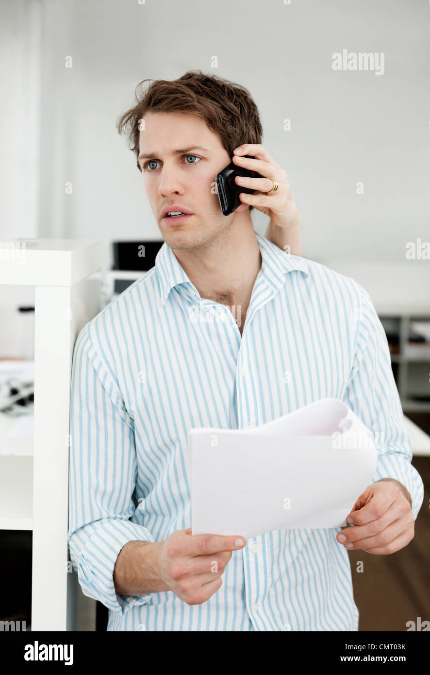 Man in office holding papers and talking on phone Stock Photo - Alamy