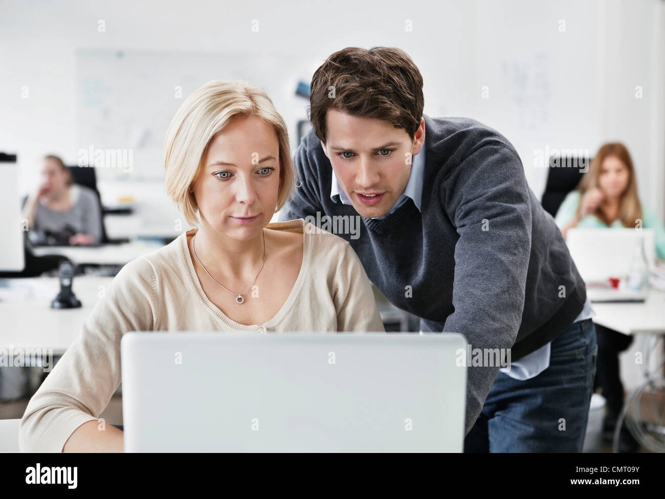 Man helping colleague with computer Stock Photo - Alamy