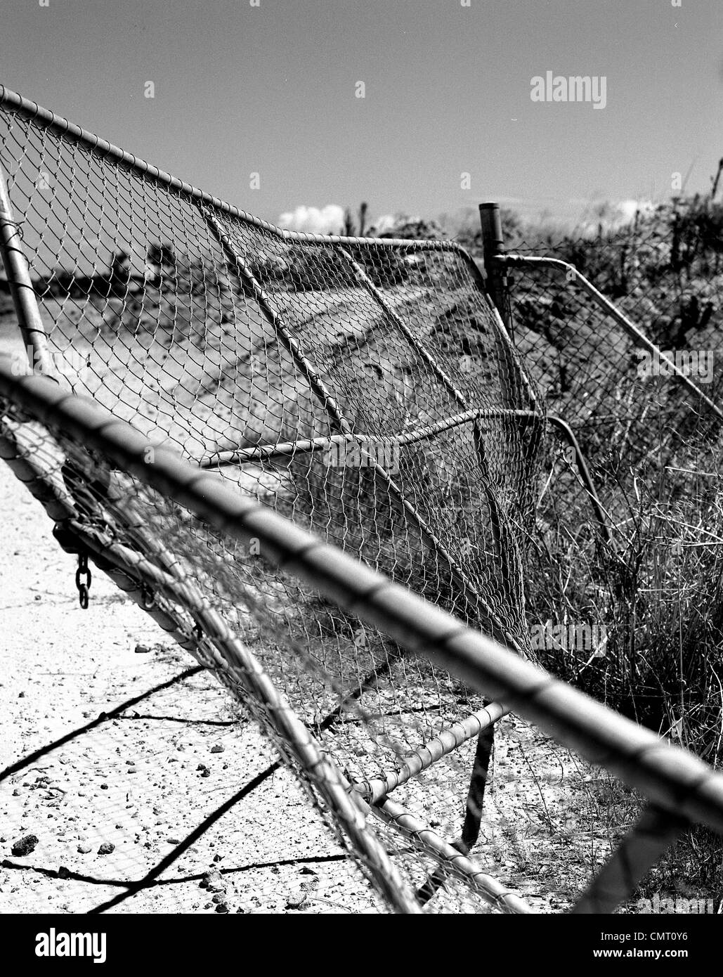 A mangled gate casts a shadow on waste ground Stock Photo - Alamy