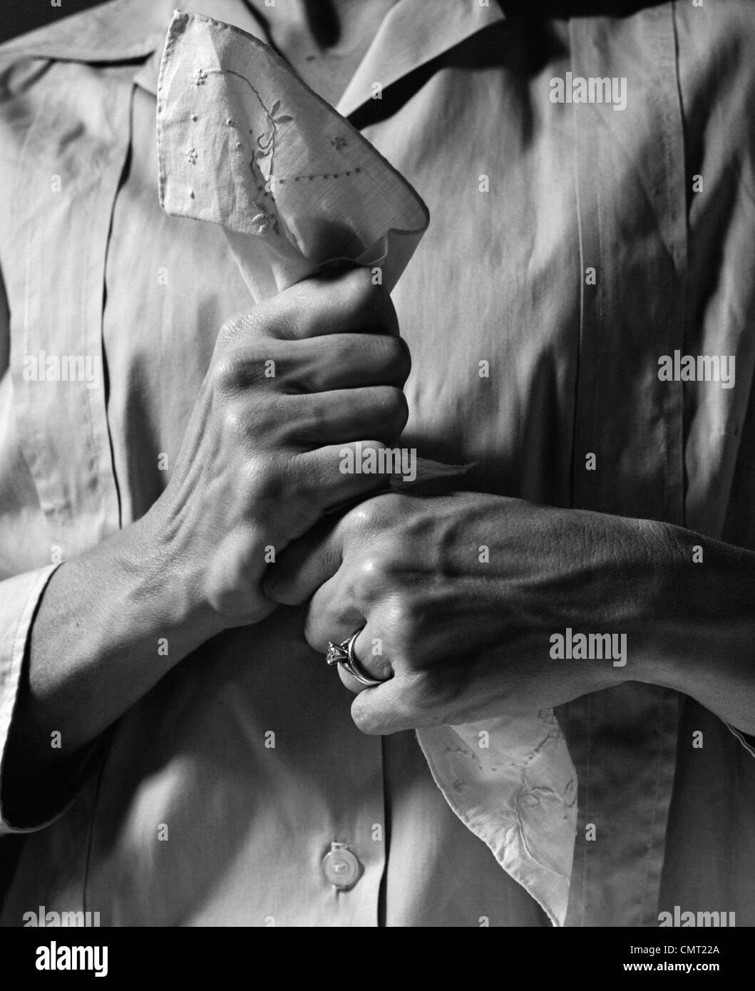 1960s WOMAN'S HANDS HOLDING HANDKERCHIEF TIGHTLY IN FRONT OF CHEST ...