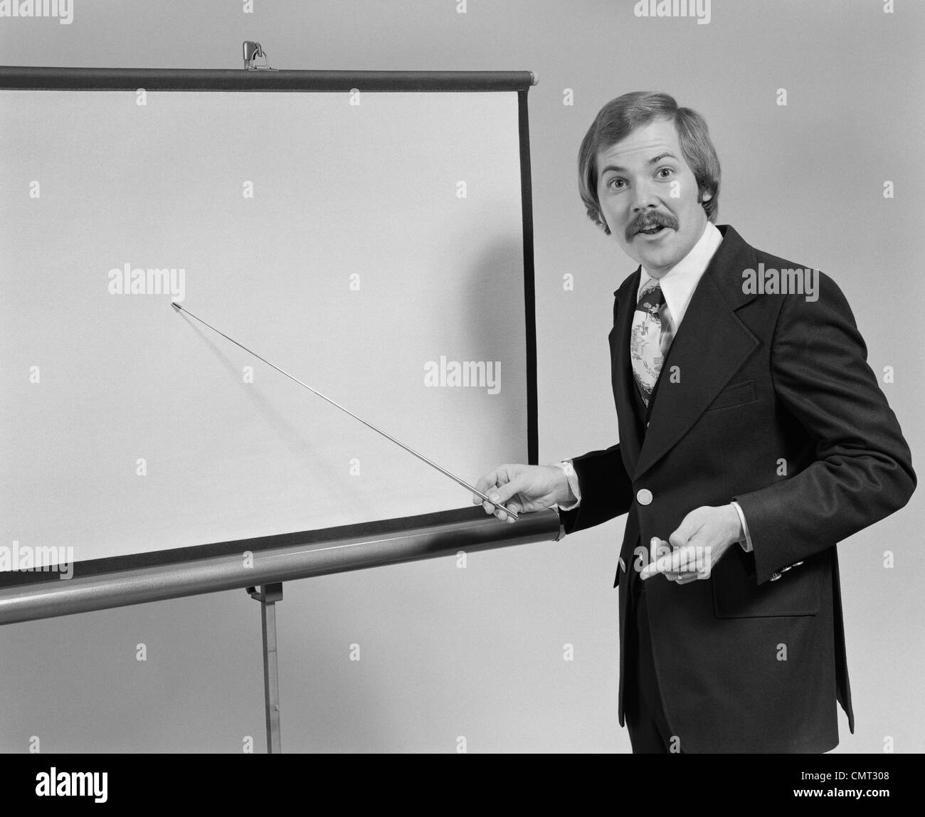 1970s YOUNG MAN SPEAKING POINTING TO BLANK SLIDE SCREEN FOR ...