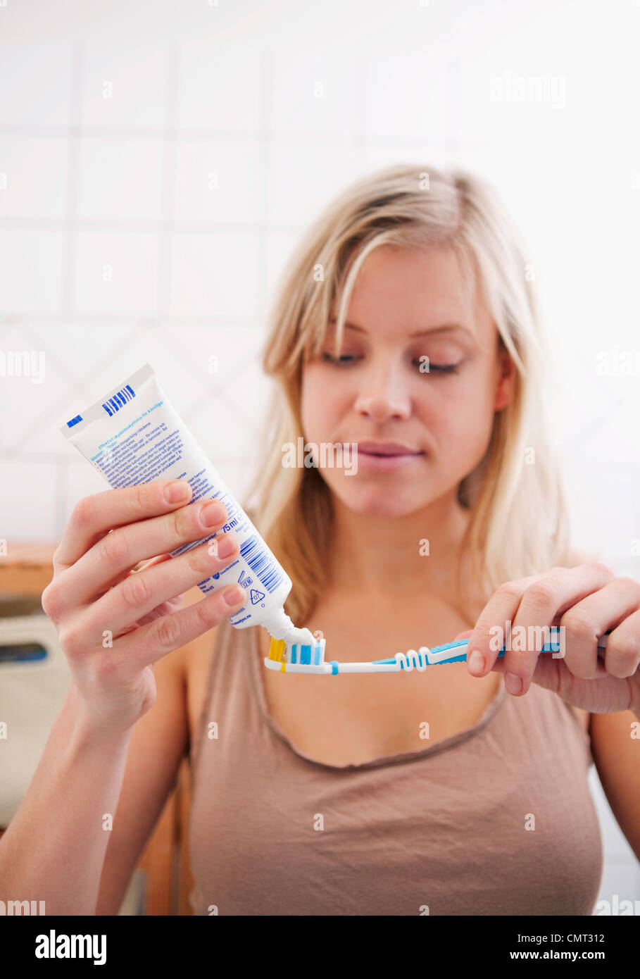 Woman putting toothpaste on toothbrush Stock Photo - Alamy