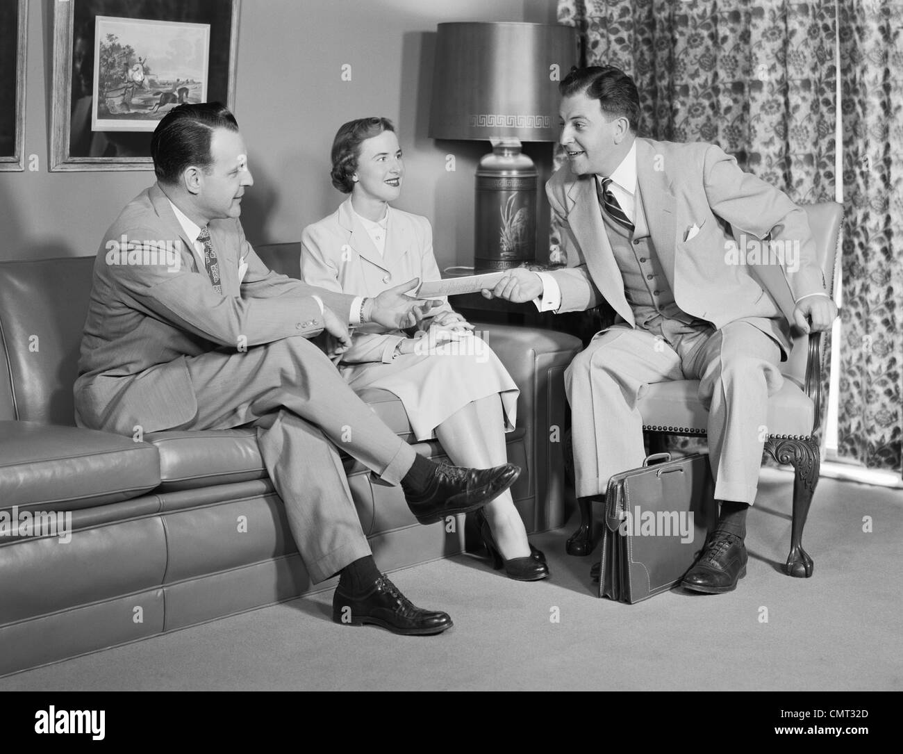 1950s COUPLE SITTING ON COUCH TALKING TO SMILING INSURANCE SALESMAN ...