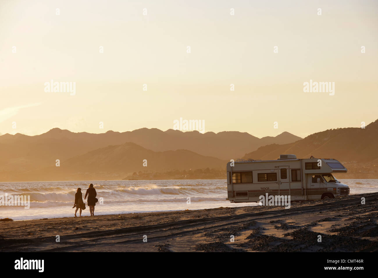 People stroll on California beach at sunset with RV motorhome Stock ...