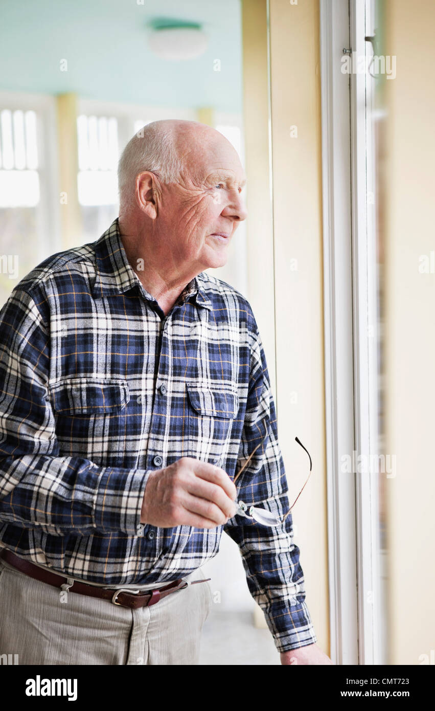 Elderly man looking out through window Stock Photo - Alamy