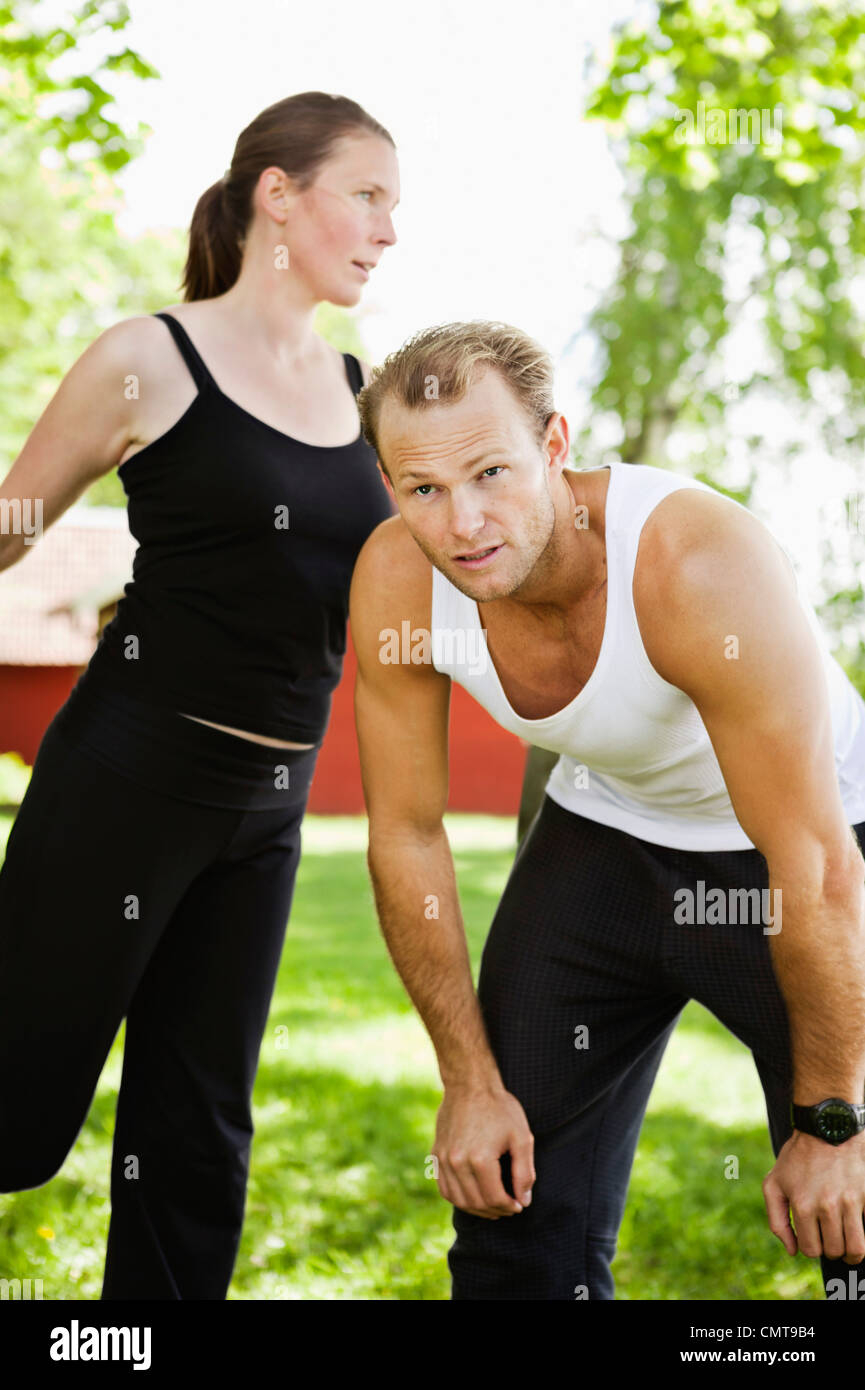 Woman exercising while leaning on tired man Stock Photo - Alamy