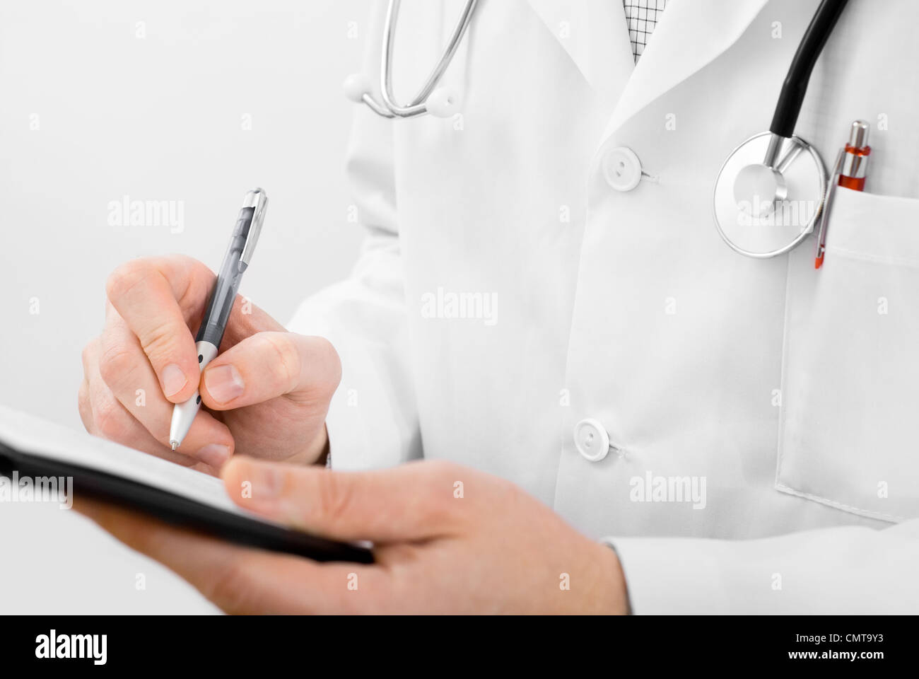 Doctor with stethoscope and clipboard writing something Stock Photo - Alamy