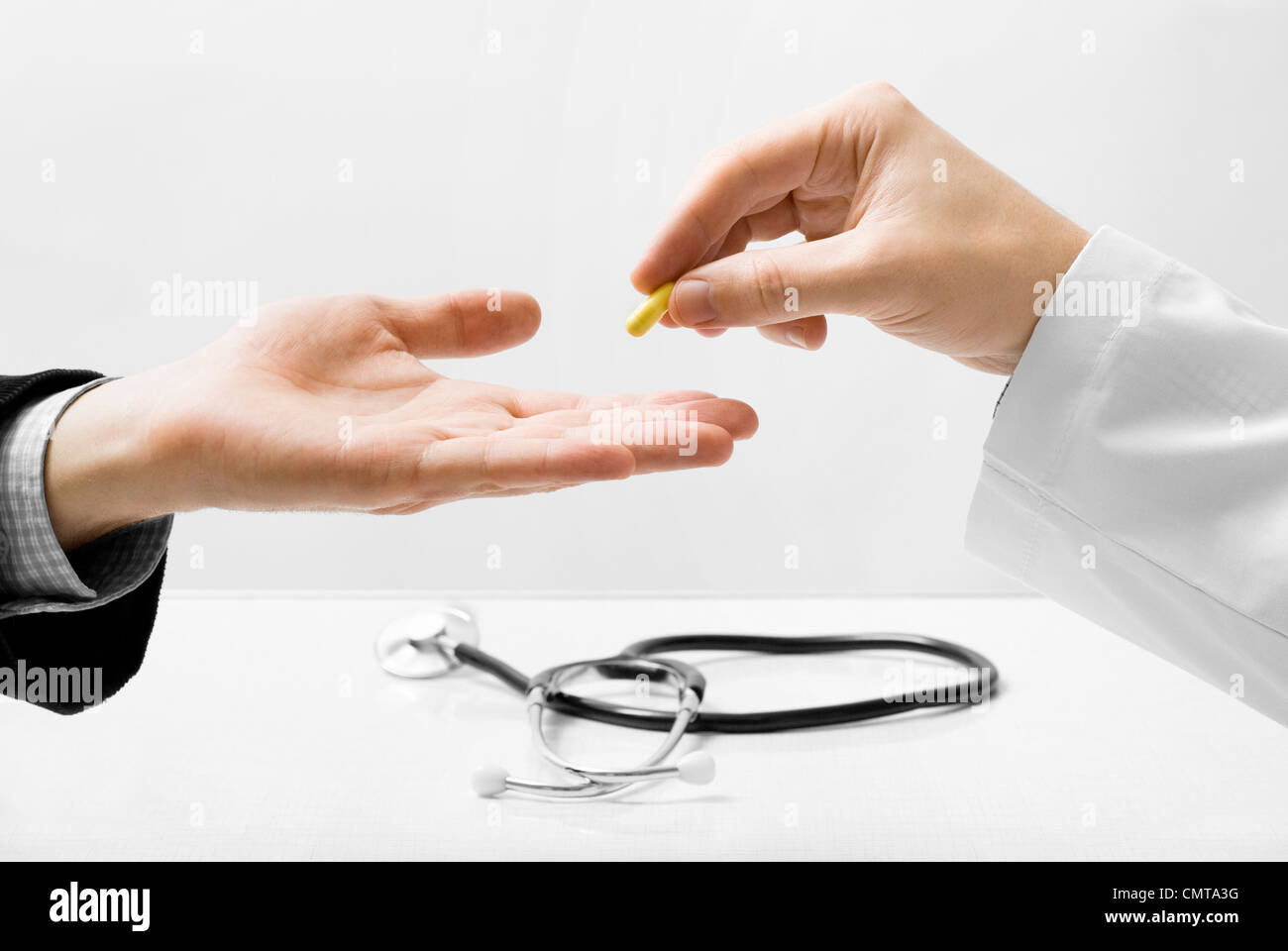 Male doctor giving small pill to patient Stock Photo - Alamy