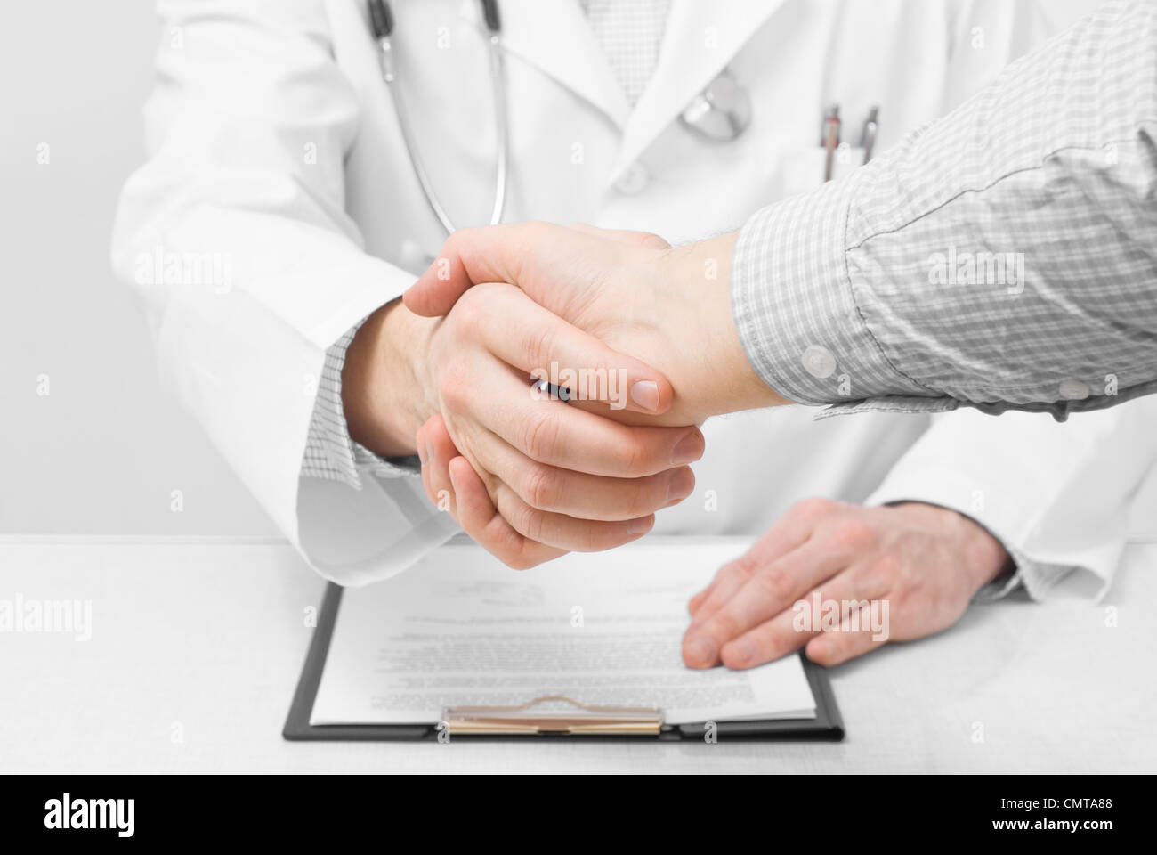 Doctor with stethoscope and clipboard shaking patients hand Stock Photo ...