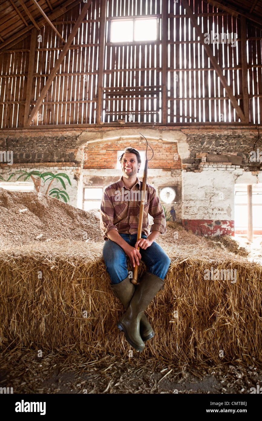 Farmer sitting on hay bale Stock Photo - Alamy