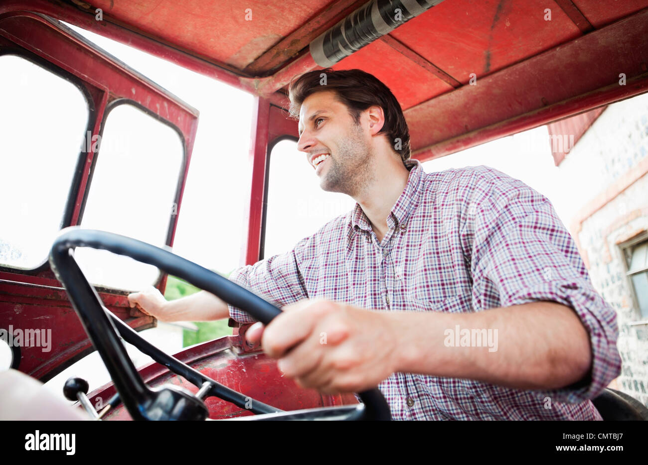 Low angle view of man smiling in tractor Stock Photo - Alamy