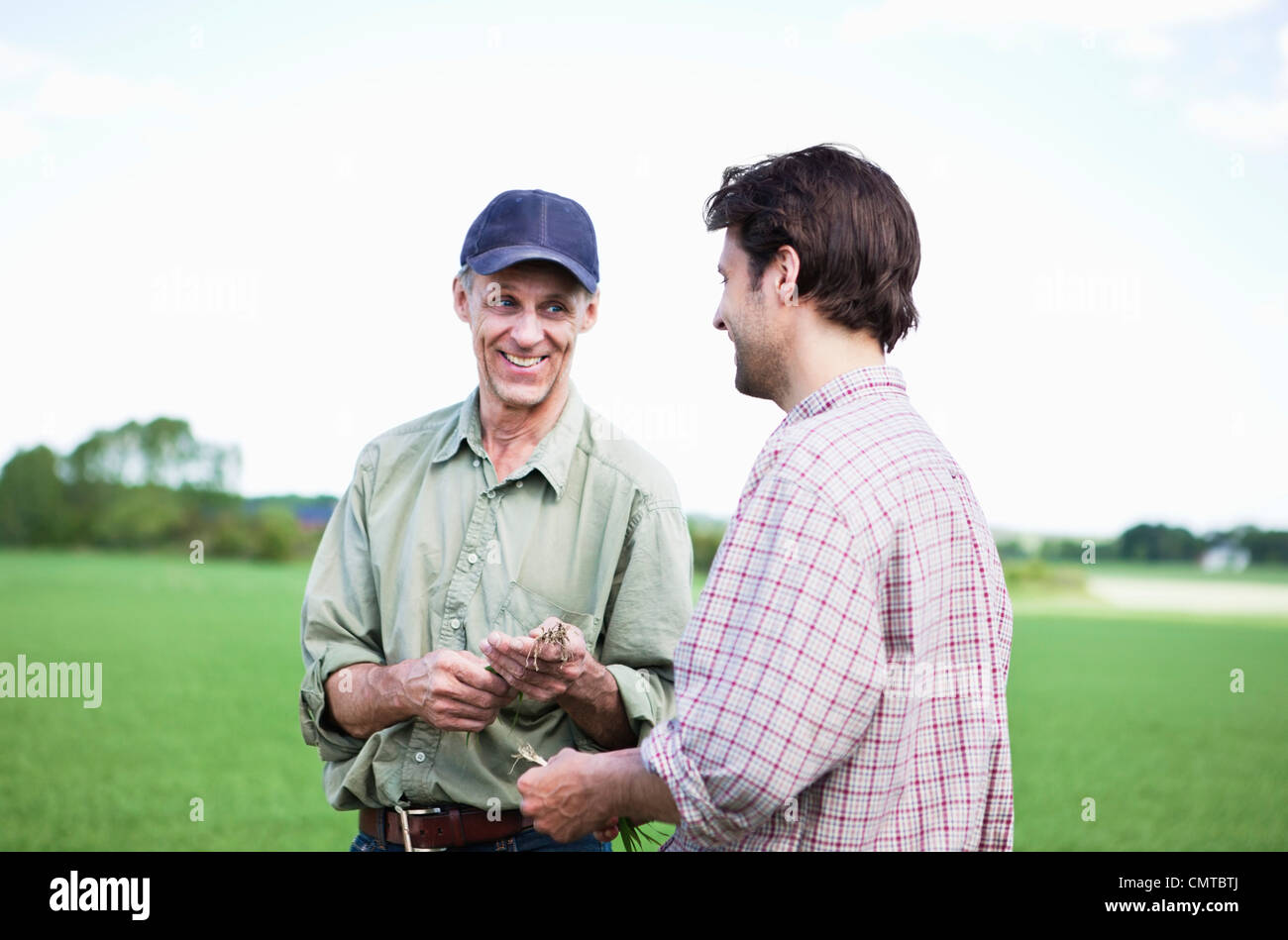 Two men smiling and holding roots Stock Photo - Alamy
