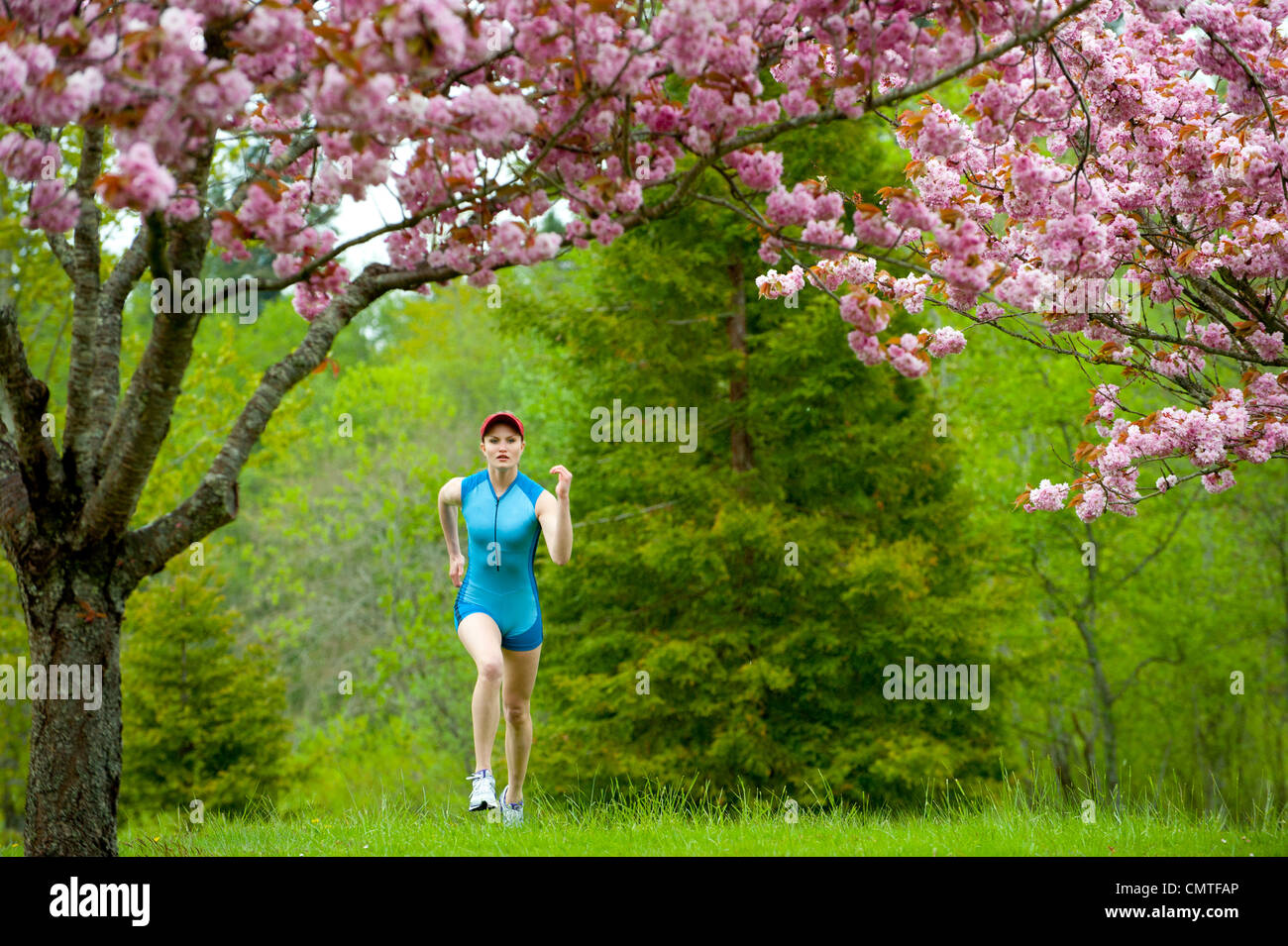 Mixed race runner jogging across grass Stock Photo - Alamy