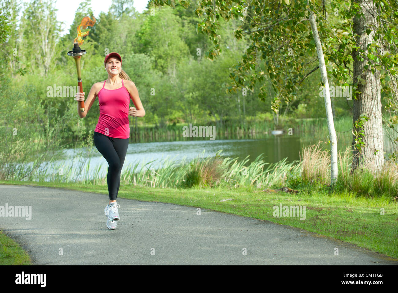Caucasian athlete running with Olympic torch on park path Stock Photo ...