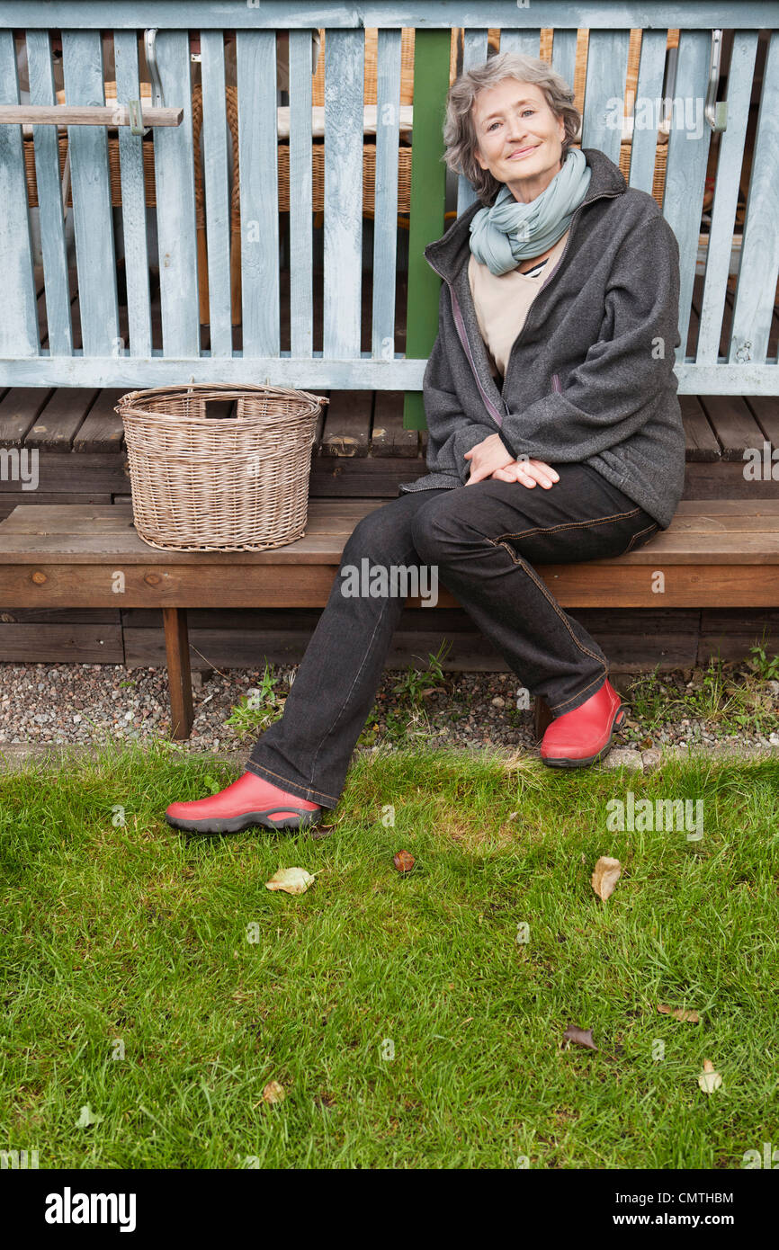 Portrait of senior woman sitting on bench looking at camera Stock Photo ...