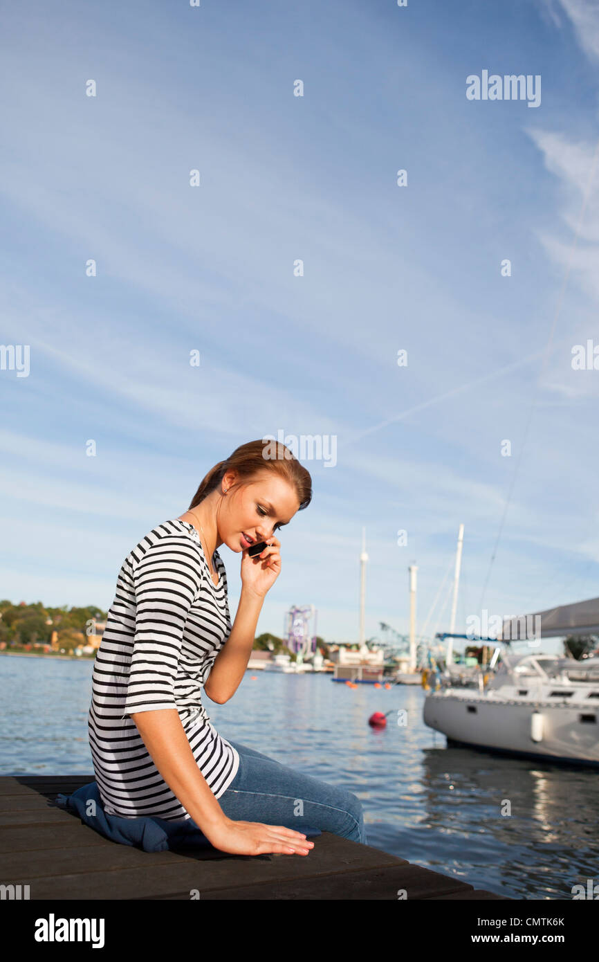 Woman looking down while talking on mobile phone Stock Photo - Alamy