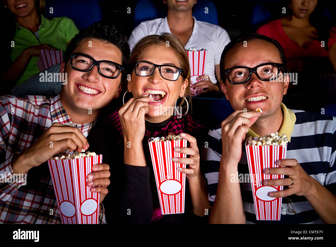 Hispanic friends enjoying popcorn at movie theater Stock Photo - Alamy
