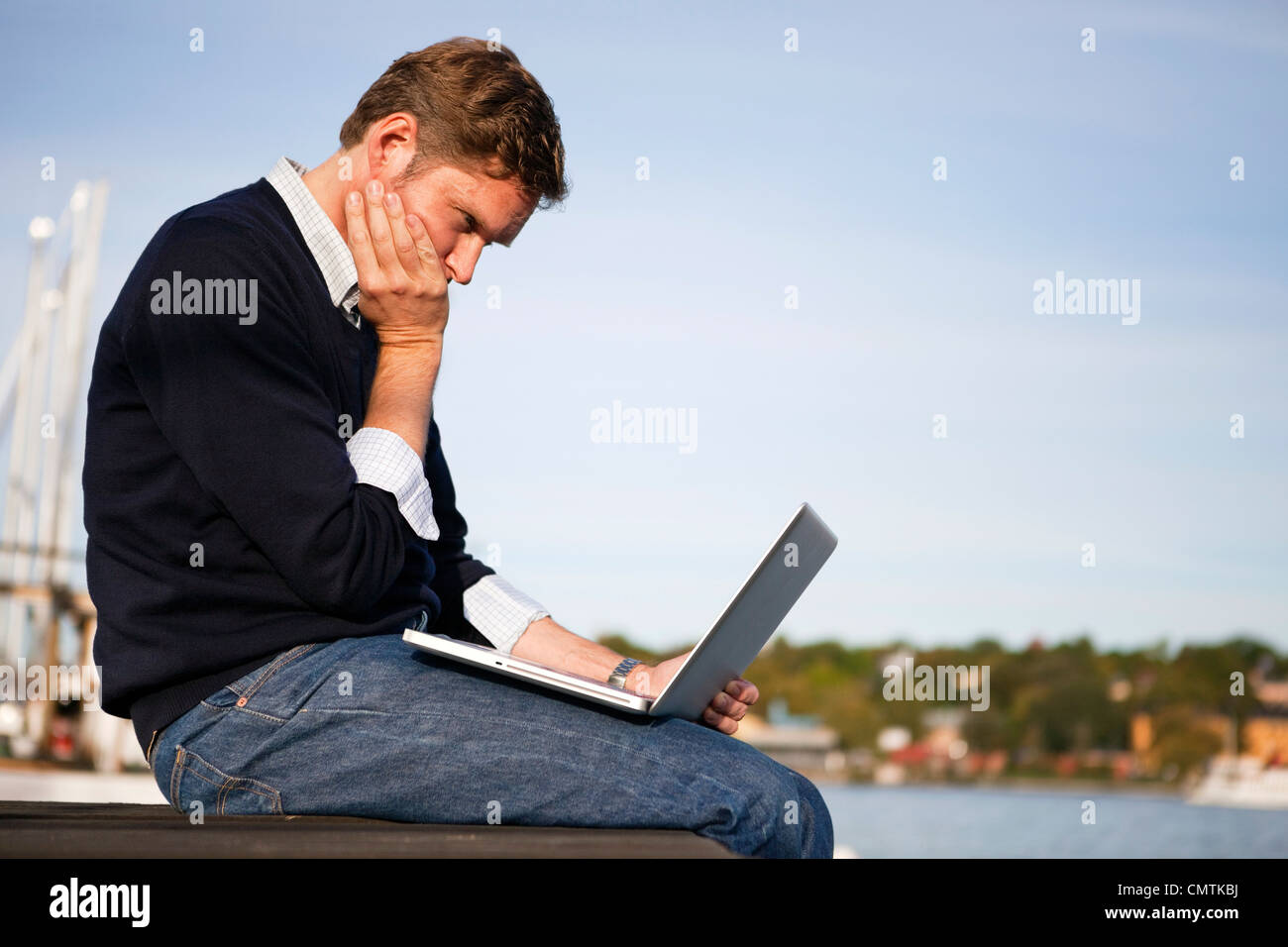 Man sitting with computer on lap Stock Photo - Alamy