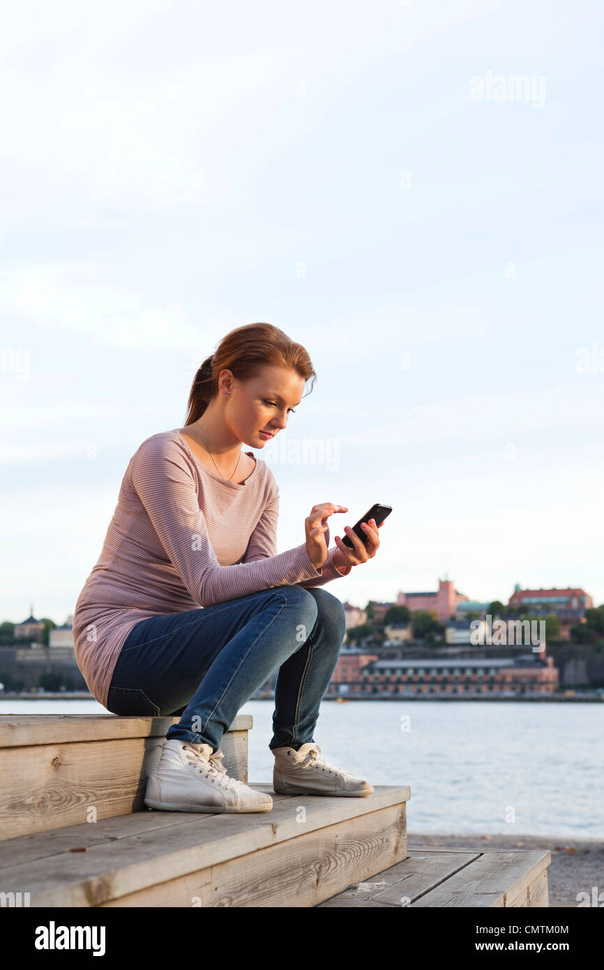 Woman sitting and using cell phone Stock Photo - Alamy