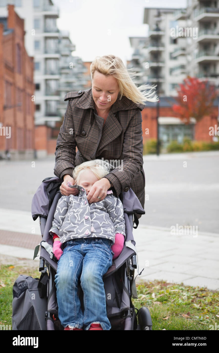Woman closing buttons of daughter's (2-3) jacket Stock Photo - Alamy