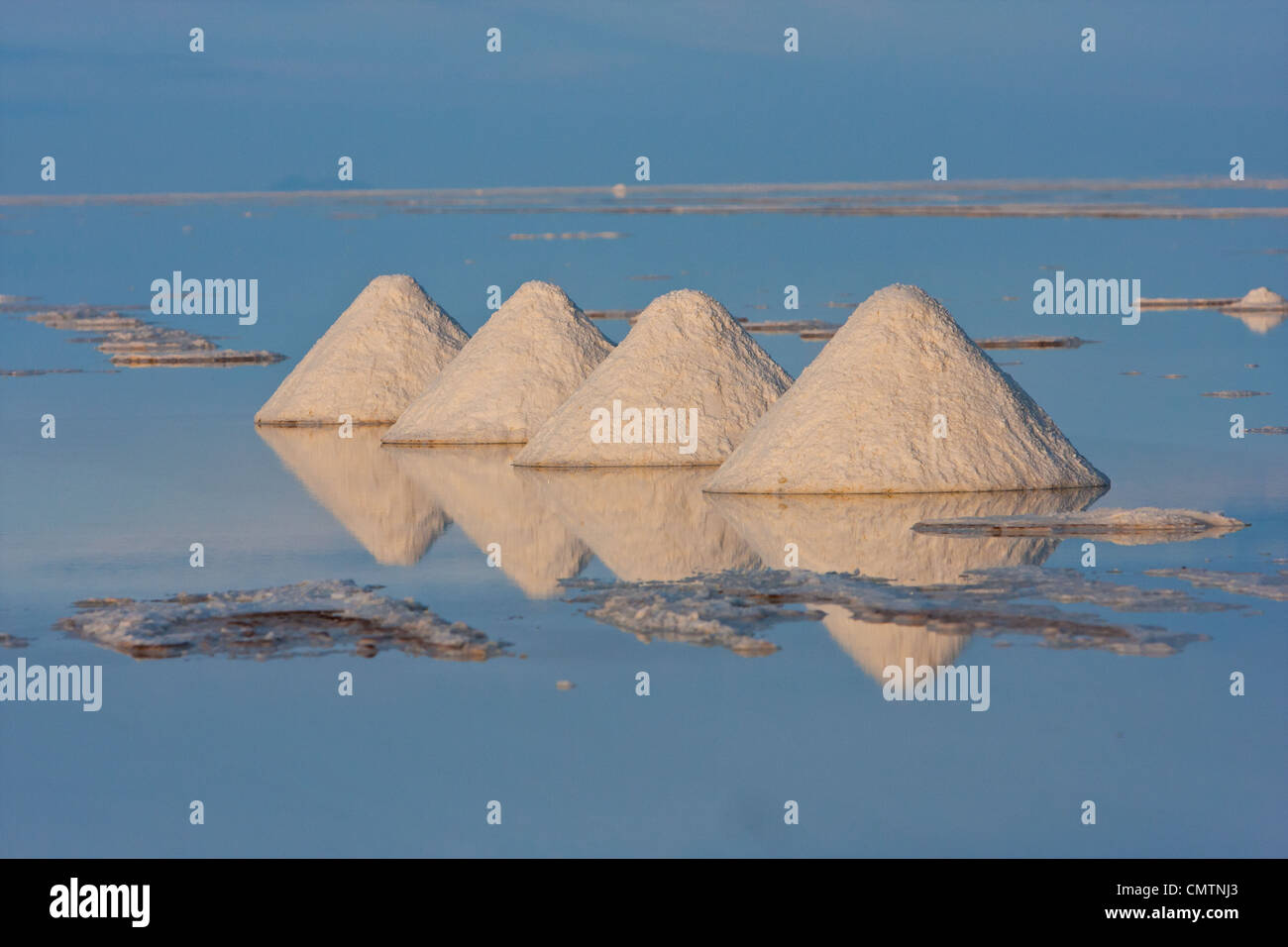 Piles of salt, drying for harvest are reflected in the mirror-like ...