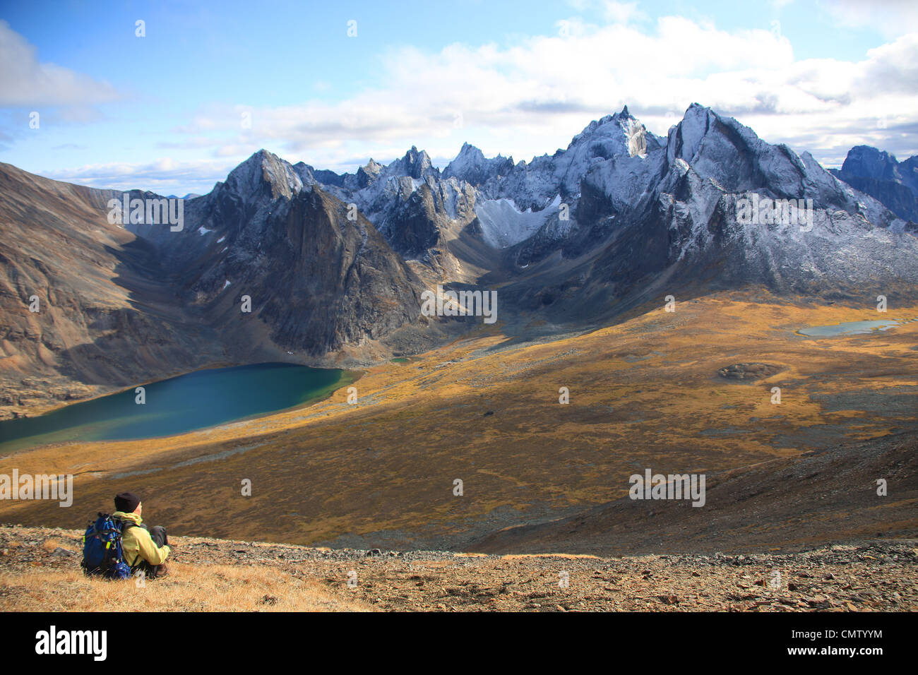 Hiker sitting on a mountain looking at Mount Monolith and Divide Lake ...