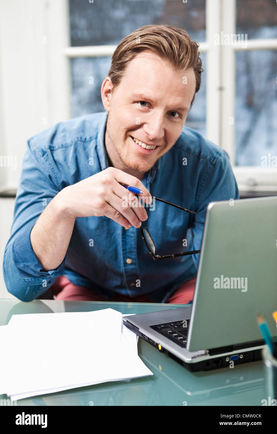 Confident businessman sitting by laptop Stock Photo - Alamy